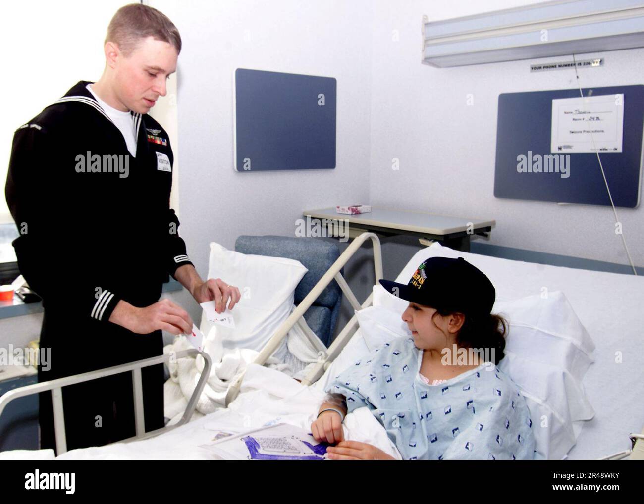 US Navy presenting a patient with a USS Saipan (LHA 2) command ball cap ...