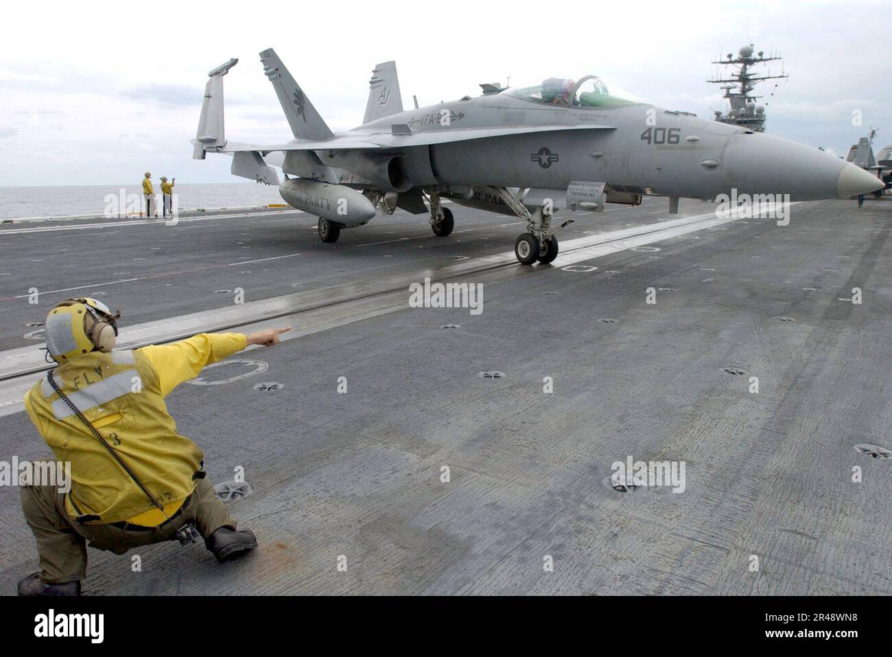 US Navy plane director guides an F-A-18 into position on the ship's ...