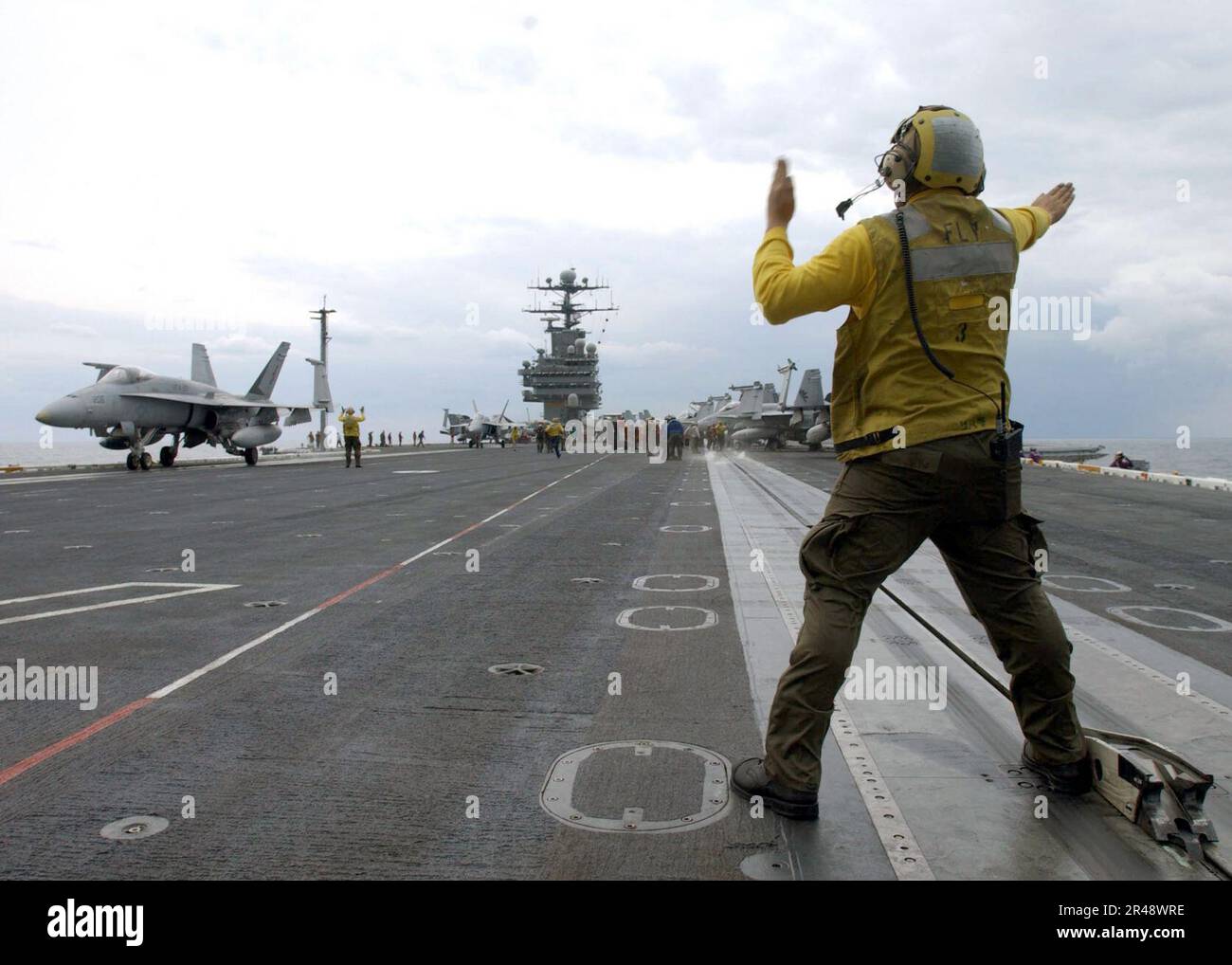 US Navy plane director guides an F-A-18 into position on the ship's ...