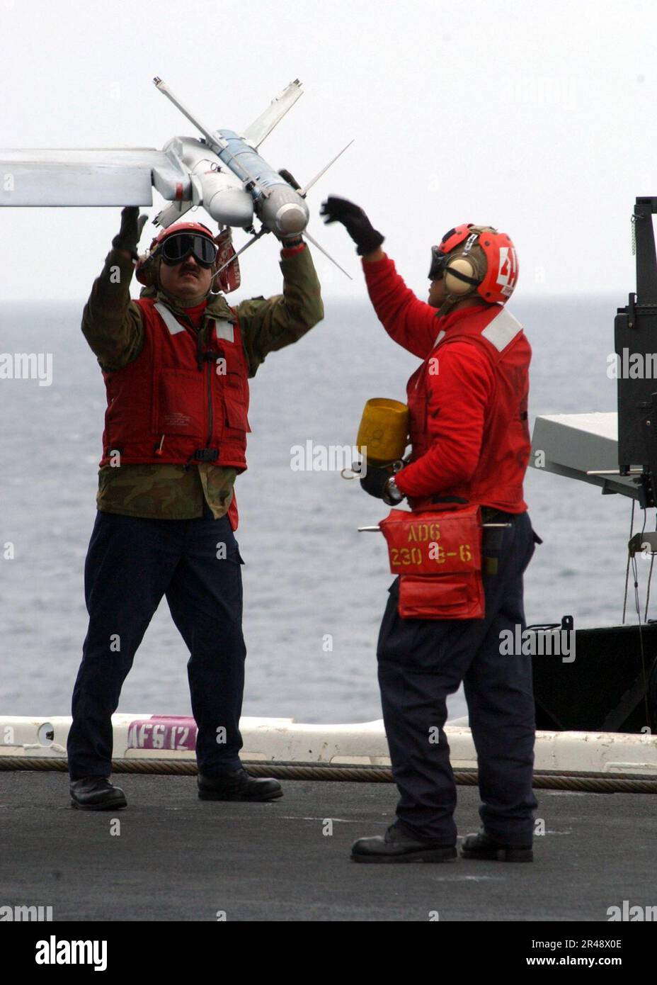 US Navy Aviation Ordnancemen secure ordnance to the wing of an F-A-18 ...