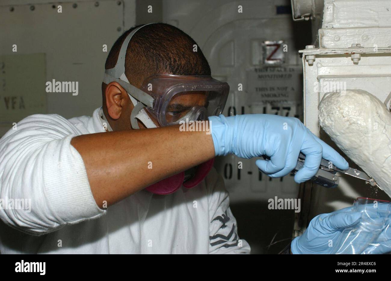 US Navy Damage Control 1st Class collects samples of lagging taken from ...