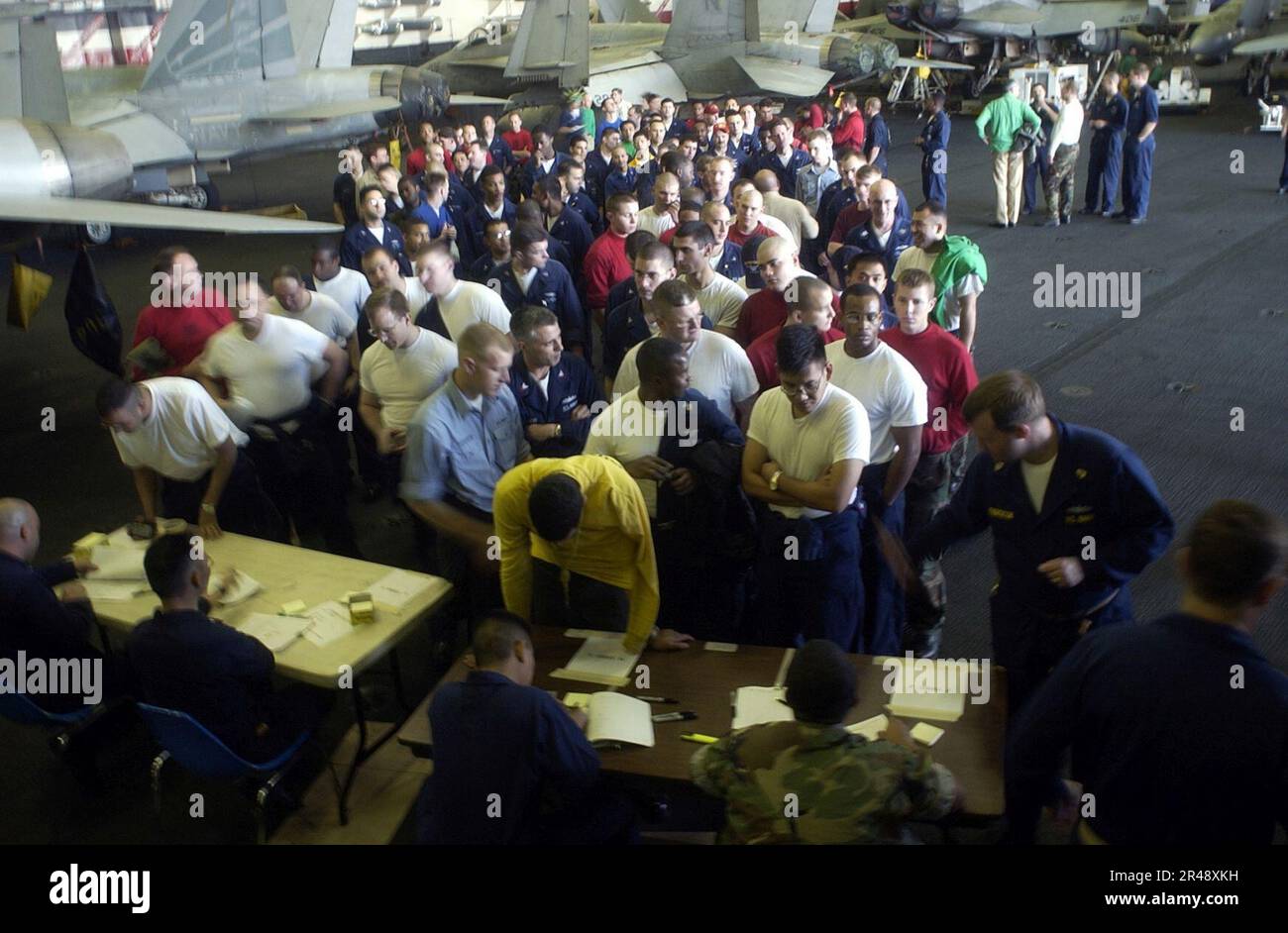 US Navy Crew members line up in the ship's hangar bay to receive the ...