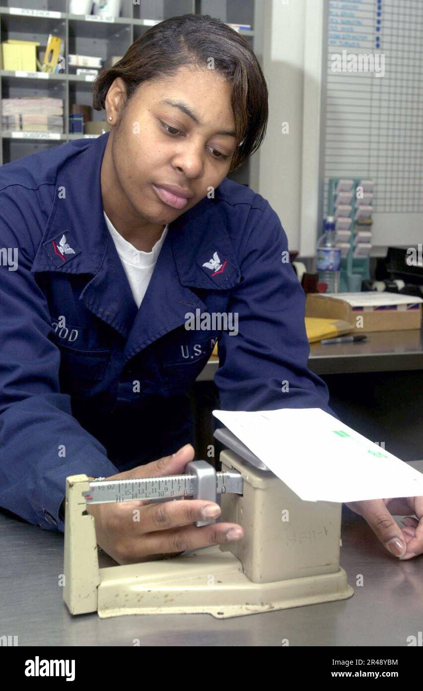 US Navy A U.S. Navy Postal Clerk checks the weight of a customers ...