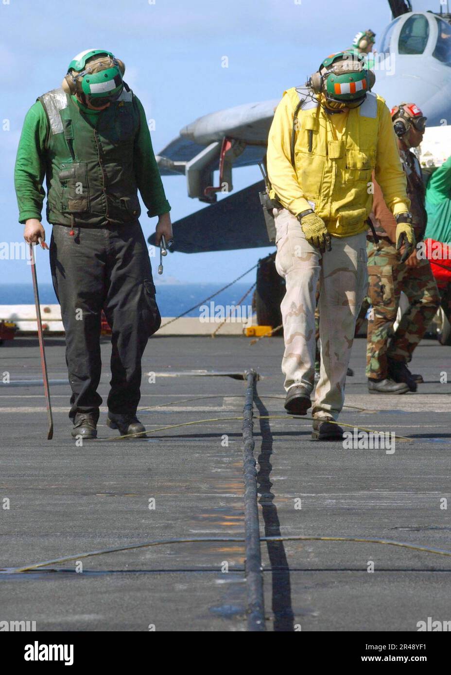 US Navy flight deck officer inspects one of the four arresting gear ...