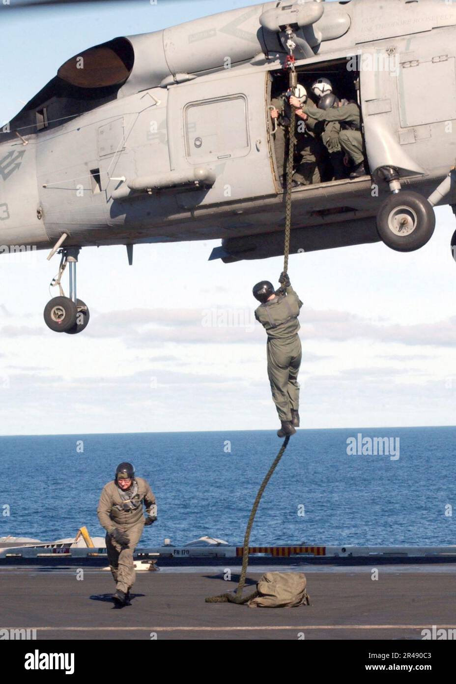 US Navy EOD team practice fast roping on the ship's flight deck from an ...