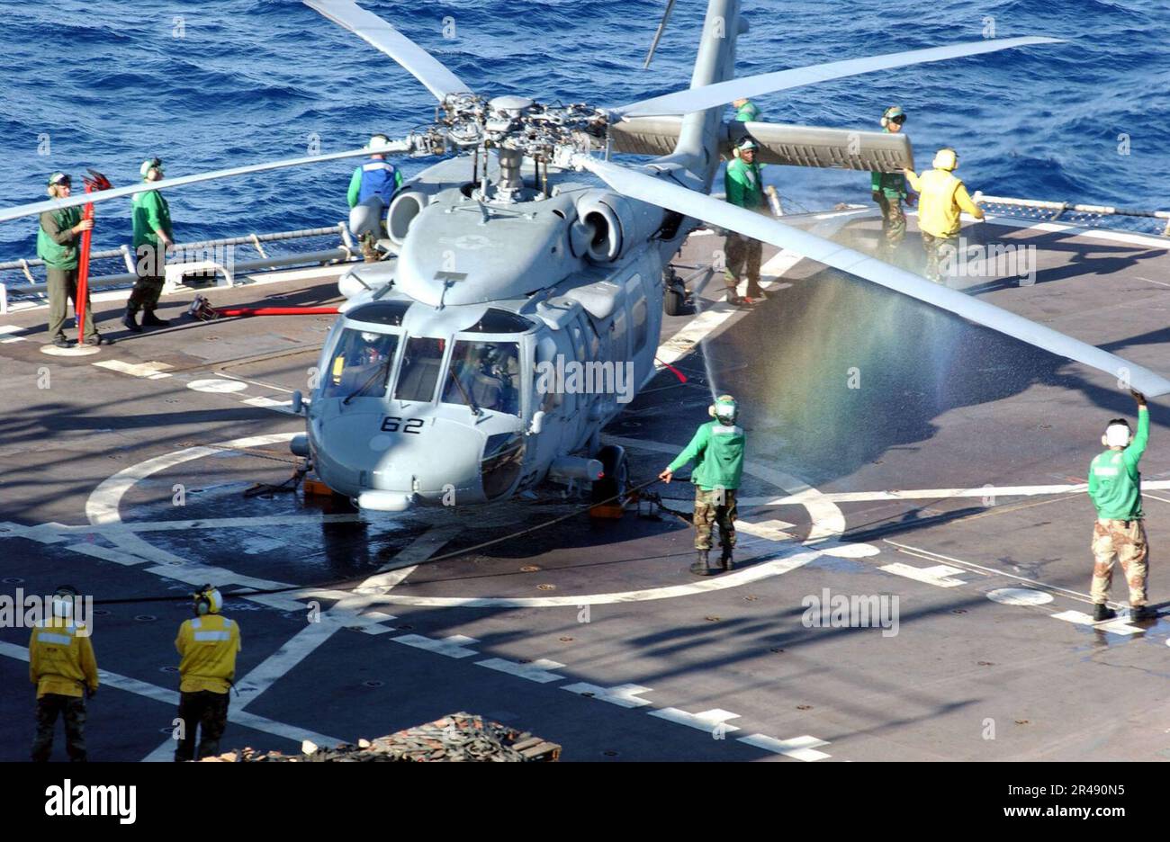 US Navy Sailors wash an MH-60 Knighthawk helicopter on the flight deck ...