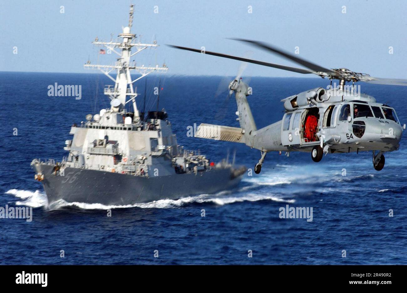US Navy An MH-60S Knighthawk helicopter flies by the guided missile ...