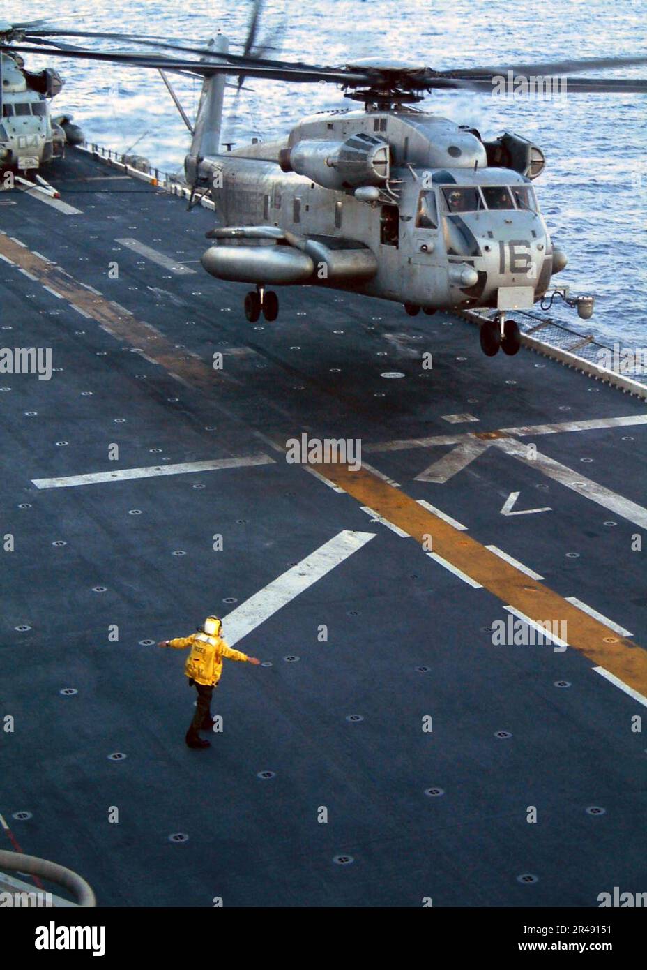 US Navy A flight deck director signals a CH-53E Super Stallion ...