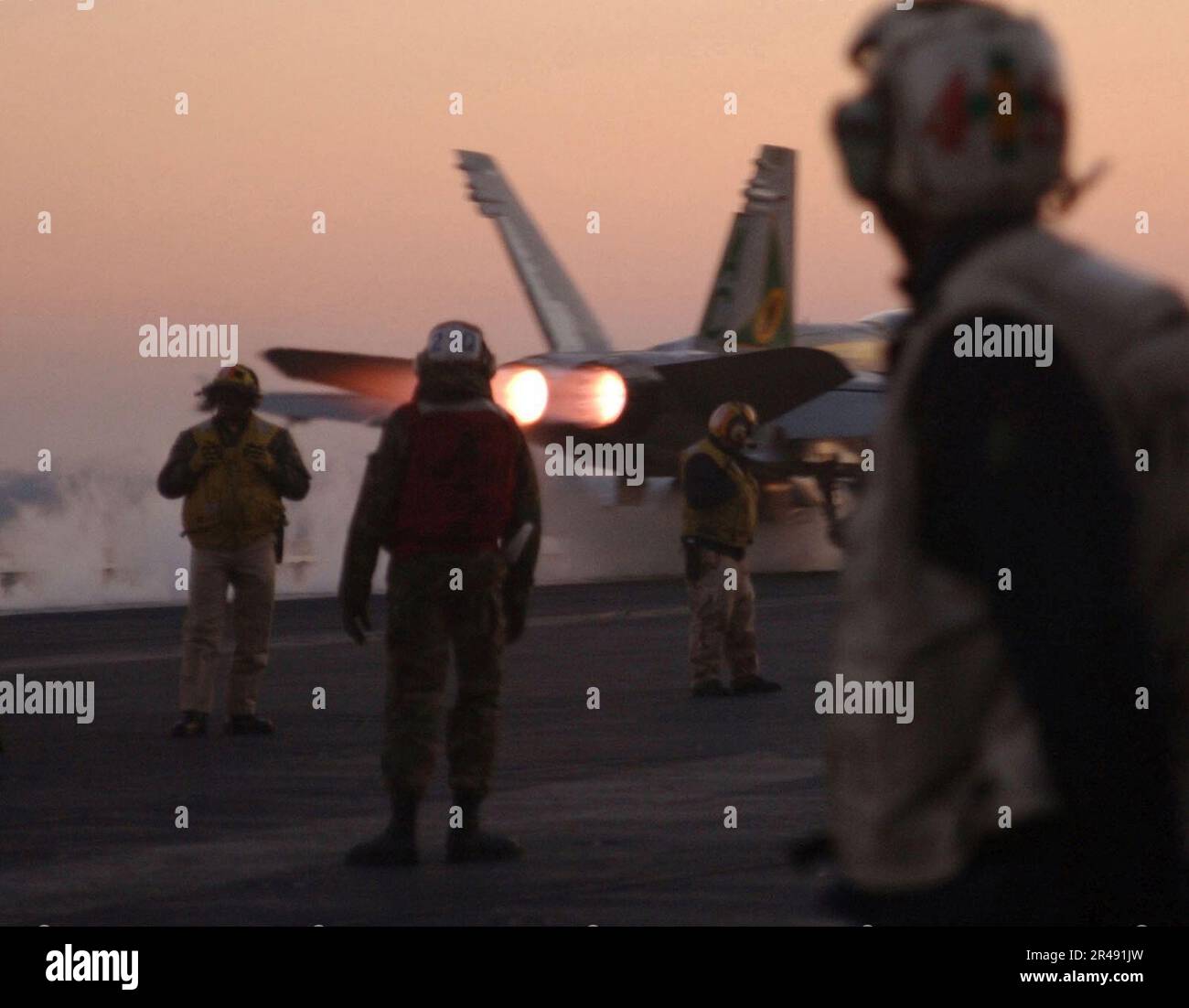US Navy Flight deck personnel stand by as an F-A-18 Hornet assigned to ...