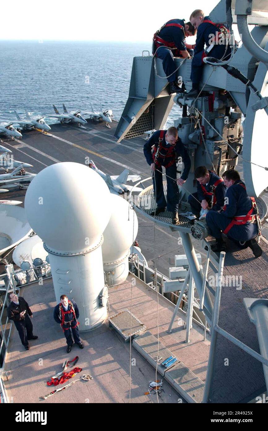 US Navy Sailors working aloft perform maintenance on the AN-SPN-43C ...