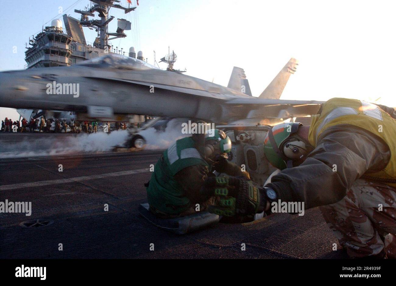 US Navy A flight deck shooter kneels down as an F-A-18C Hornet assigned ...