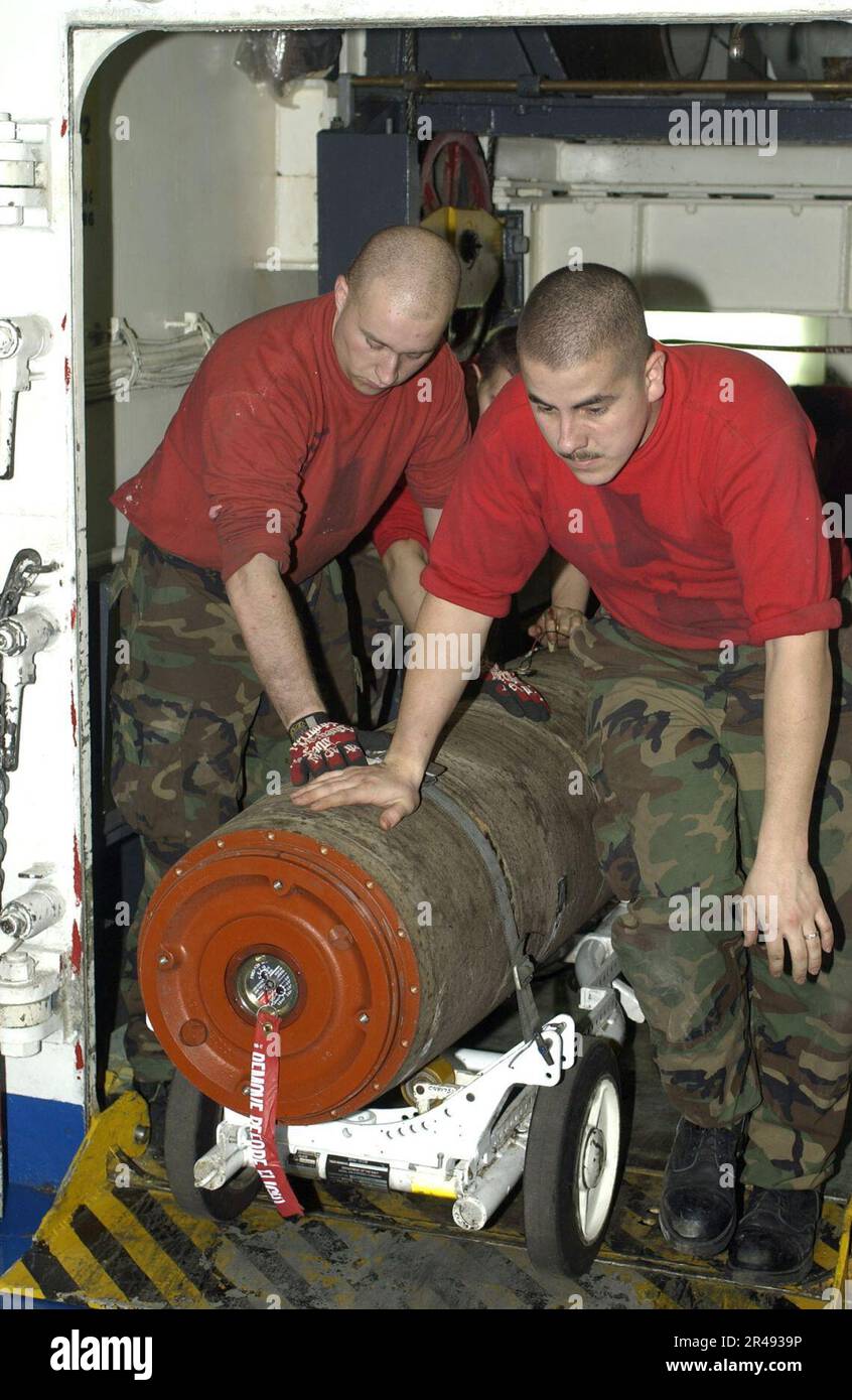 US Navy Aviation Ordnancemen move ordnance out of a weapons elevator to ...