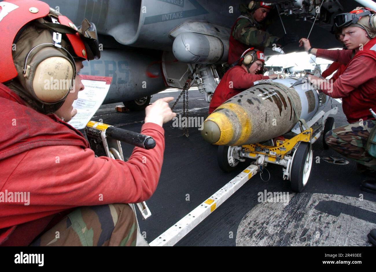 US Navy Aviation Ordnancemen rig support suspension equipment to load a ...