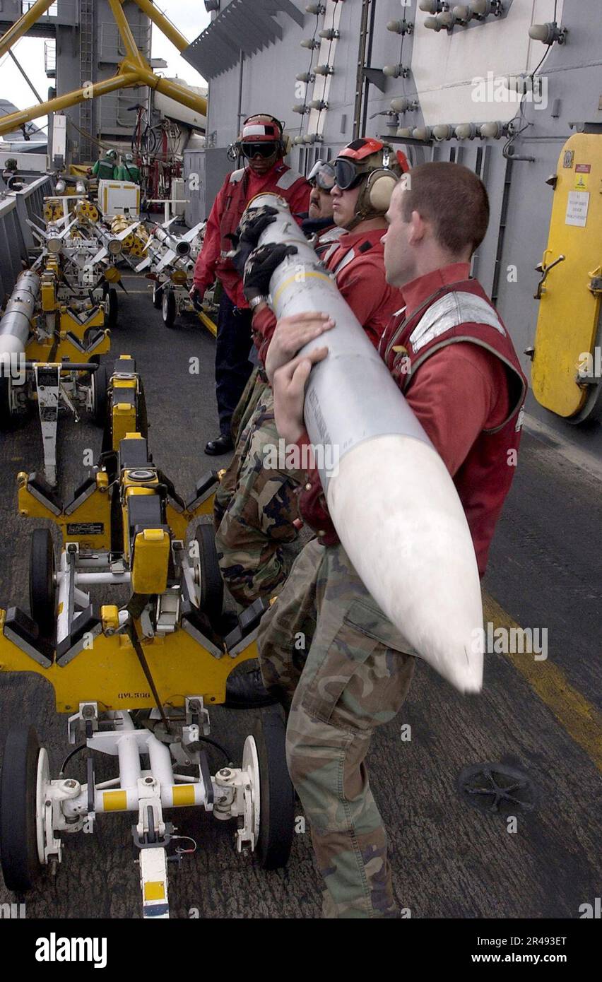 US Navy Aviation Ordnancemen work together to stage ordnance in the ...