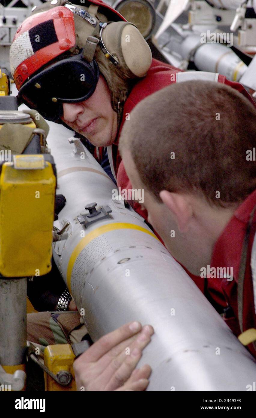 US Navy Aviation Ordnancemen work together to stage ordnance in the ...