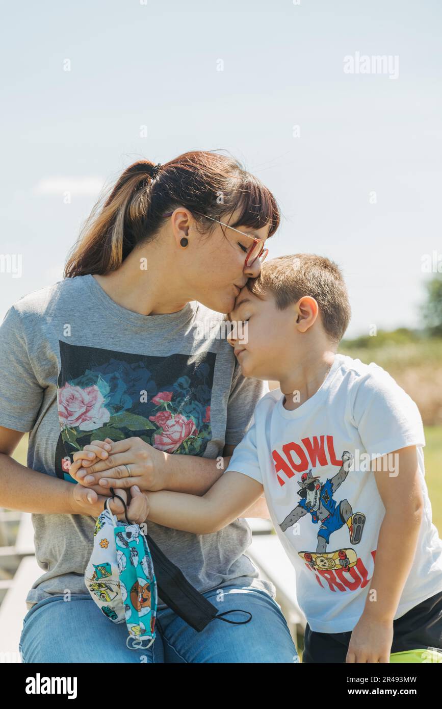 A mother and her son embrace seated in sunlight Stock Photo - Alamy
