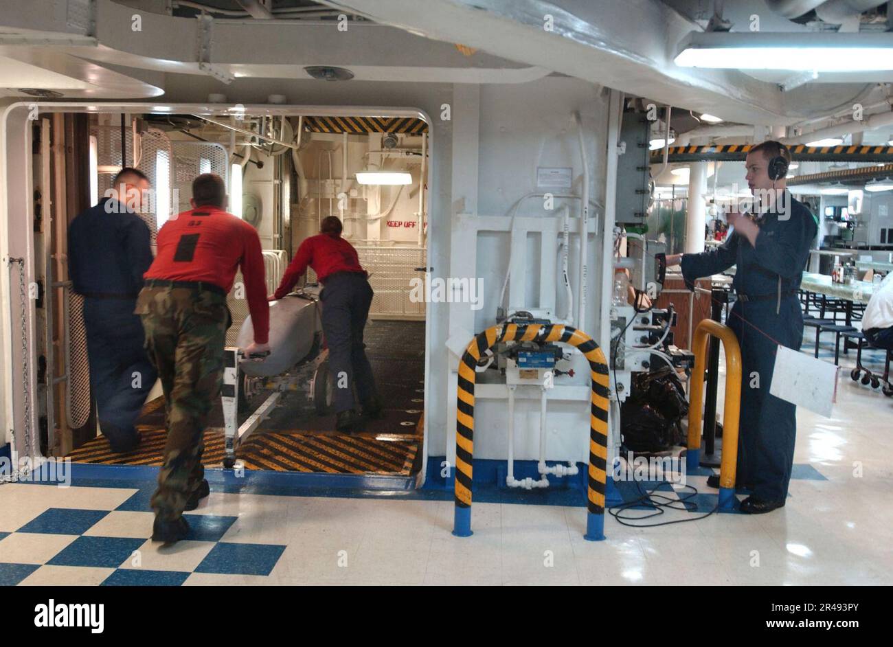 US Navy Aviation Ordnancemen transfer ordnance through the mess deck ...