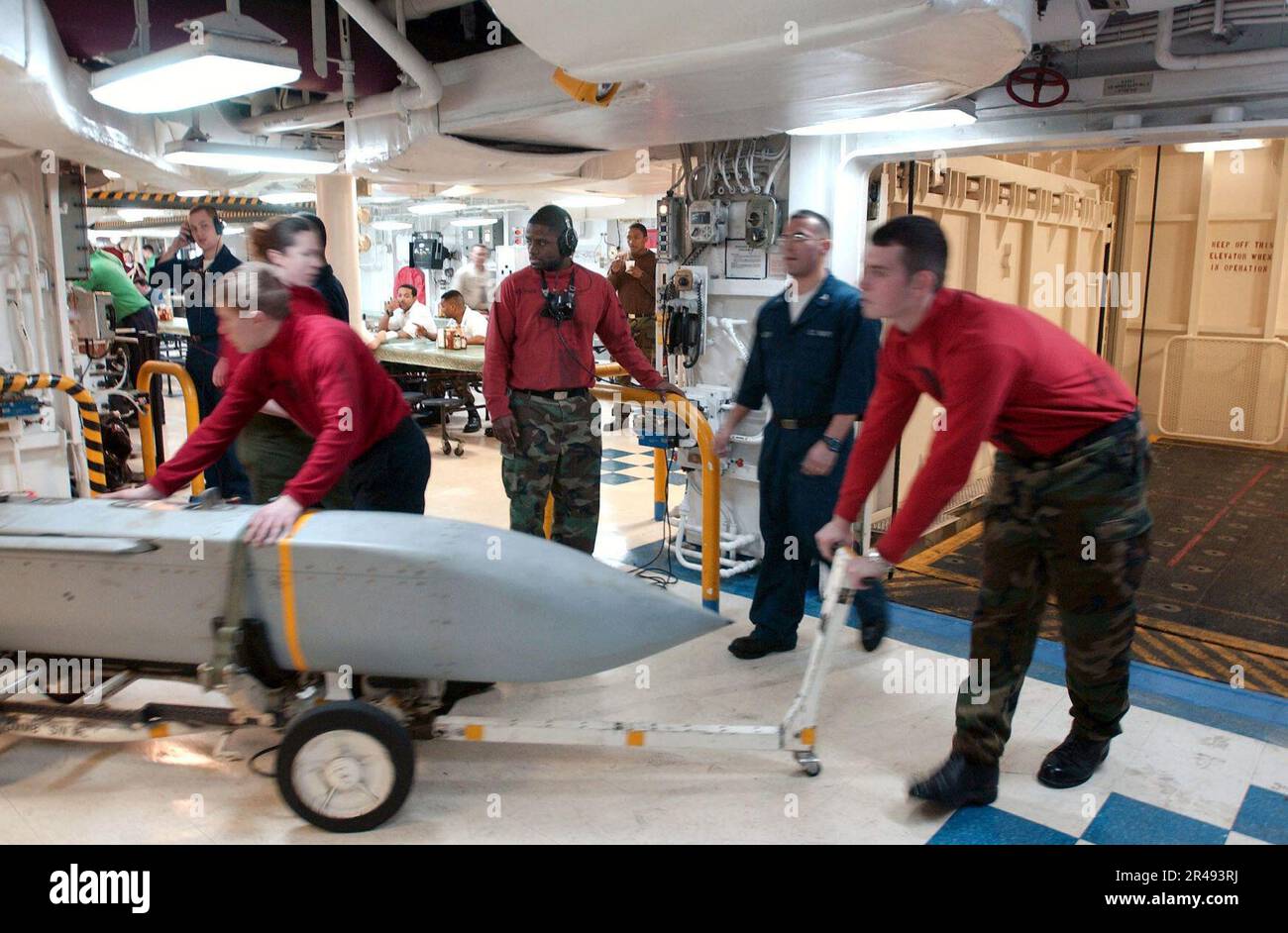 US Navy Aviation Ordnancemen transfer ordnance through the mess deck ...