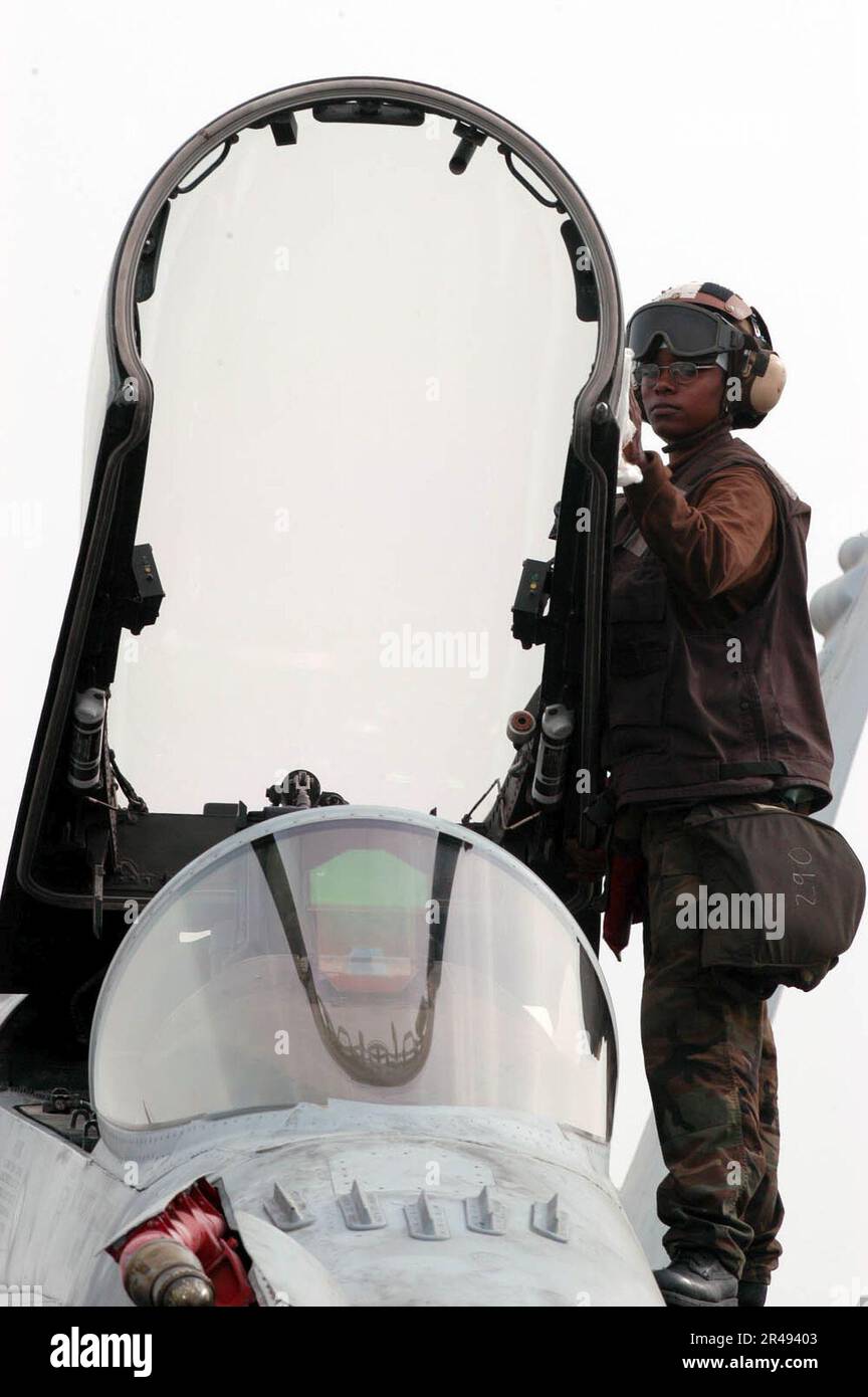 US Navy A plane captain cleans a canopy on an F-18 Hornet during ...