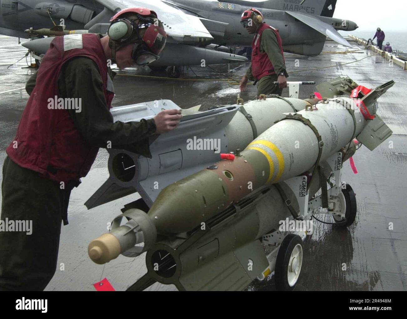 US Navy Marine Corps Ordnancemen move bombs on the flight deck aboard ...