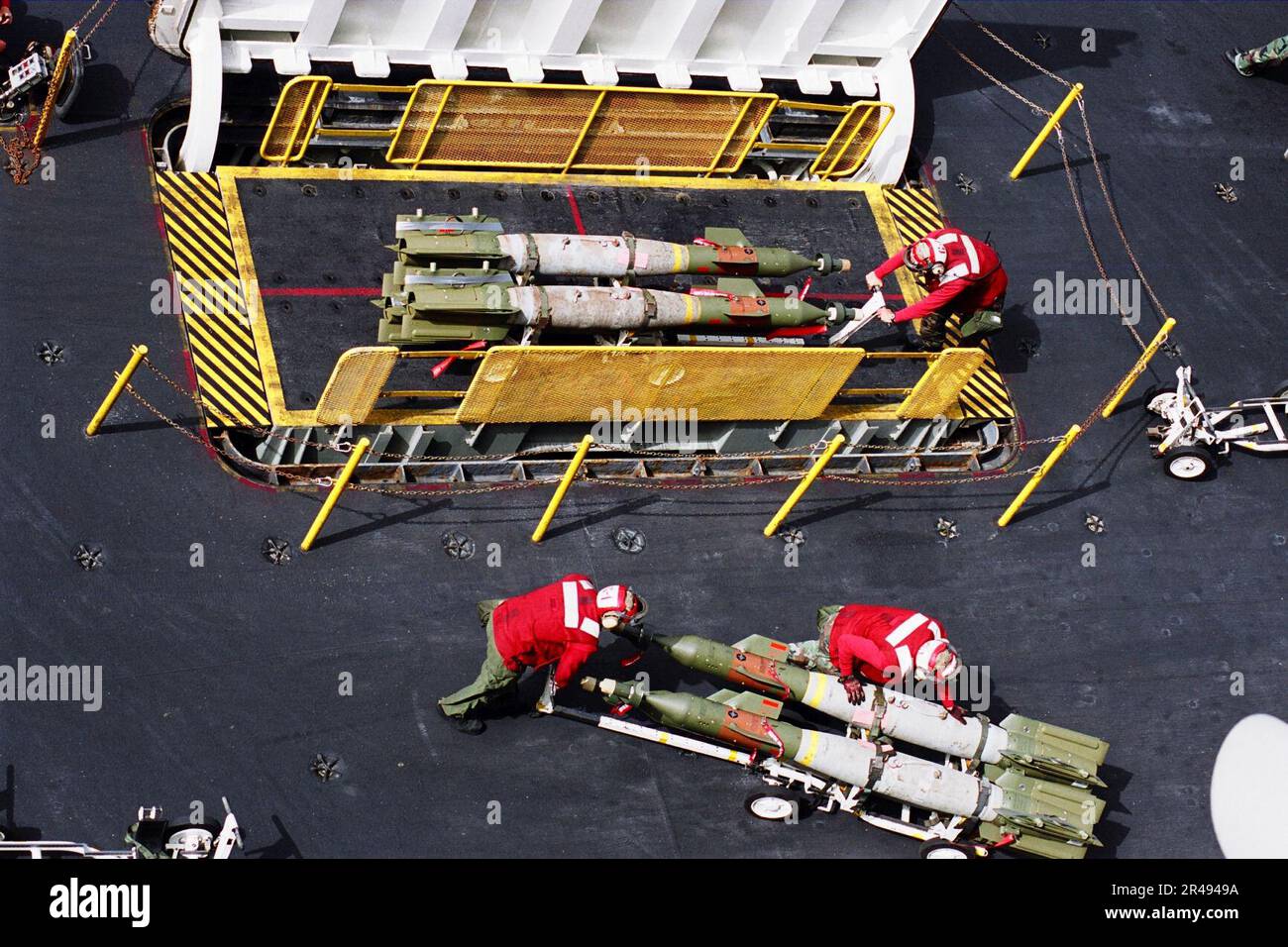 US Navy Aviation Ordnancemen move racks of precision guided ordnance ...