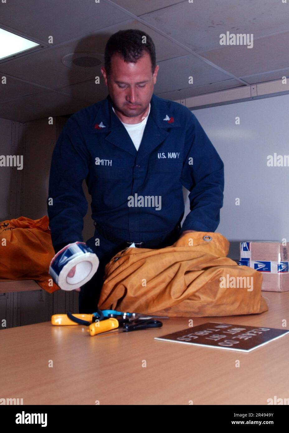 US Navy Postal Clerk 1st Class sorts packages during a mail onload ...