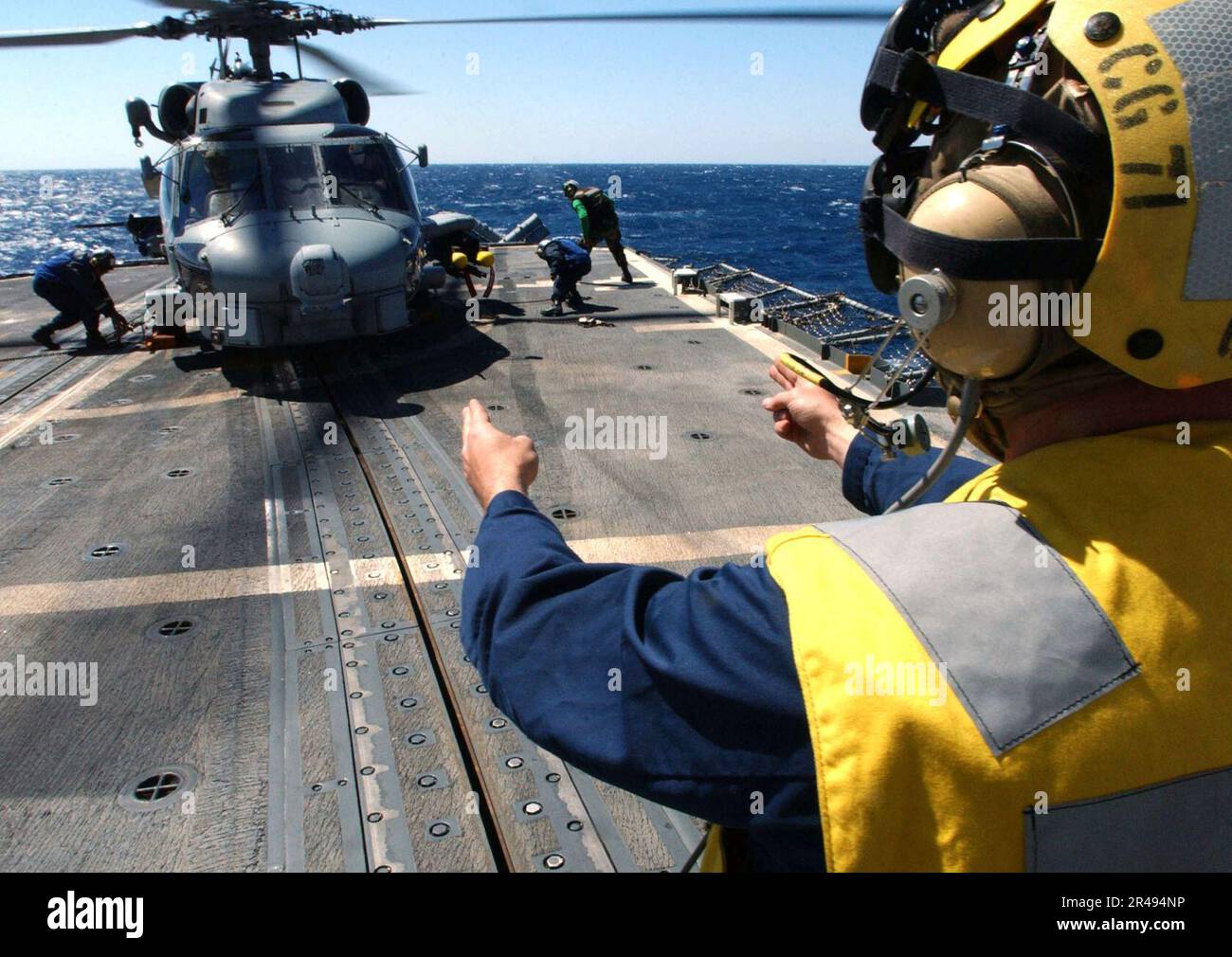 US Navy Boatswains' Mate 1st Class signals to the pilot of an SH-60B ...