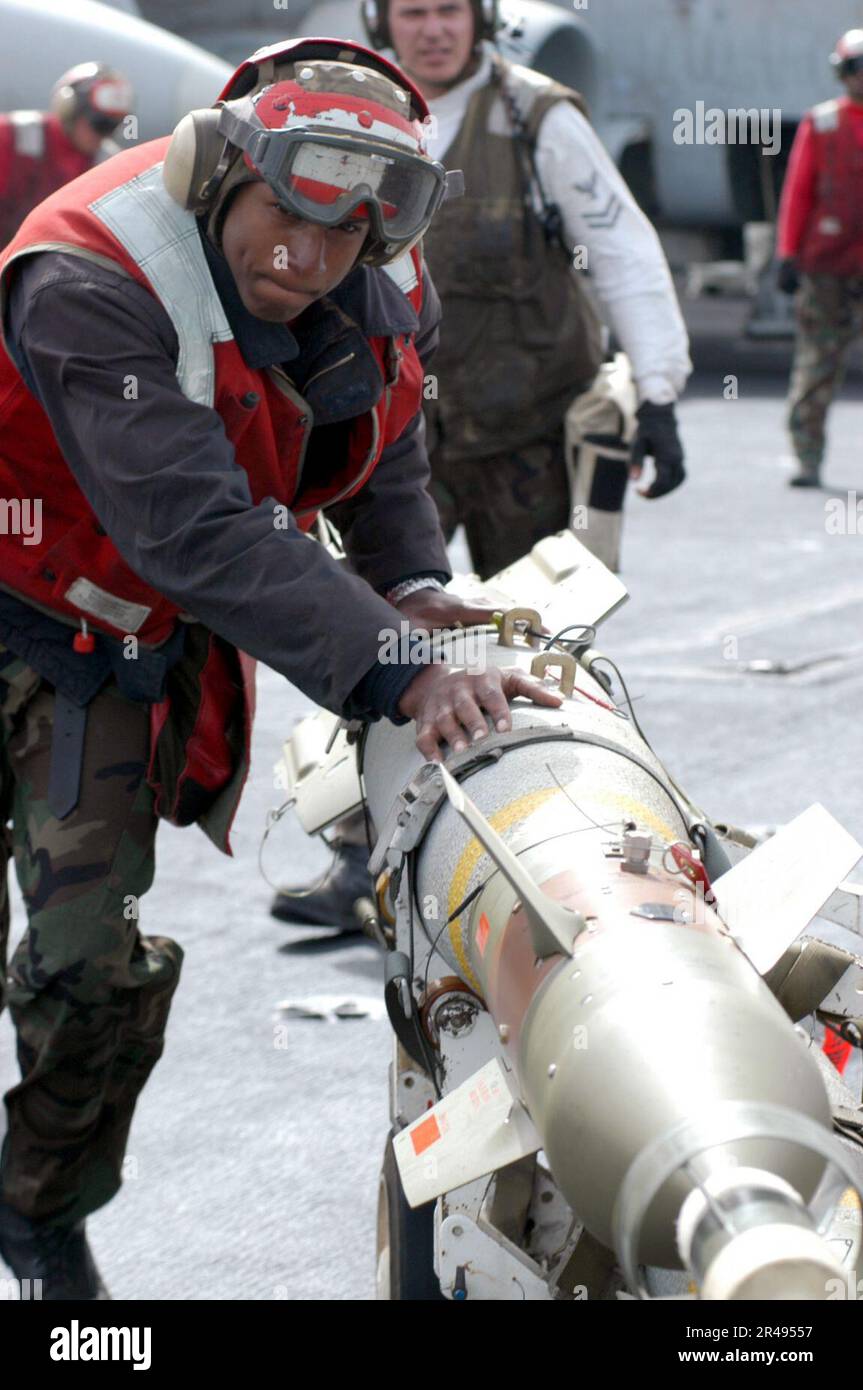 US Navy An Aviation Ordnanceman moves ordnance on the ship's flight ...