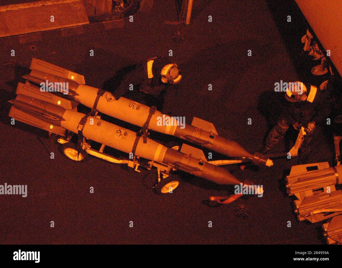 US Navy Aviation ordnancemen move bombs from a flight deck elevator to ...