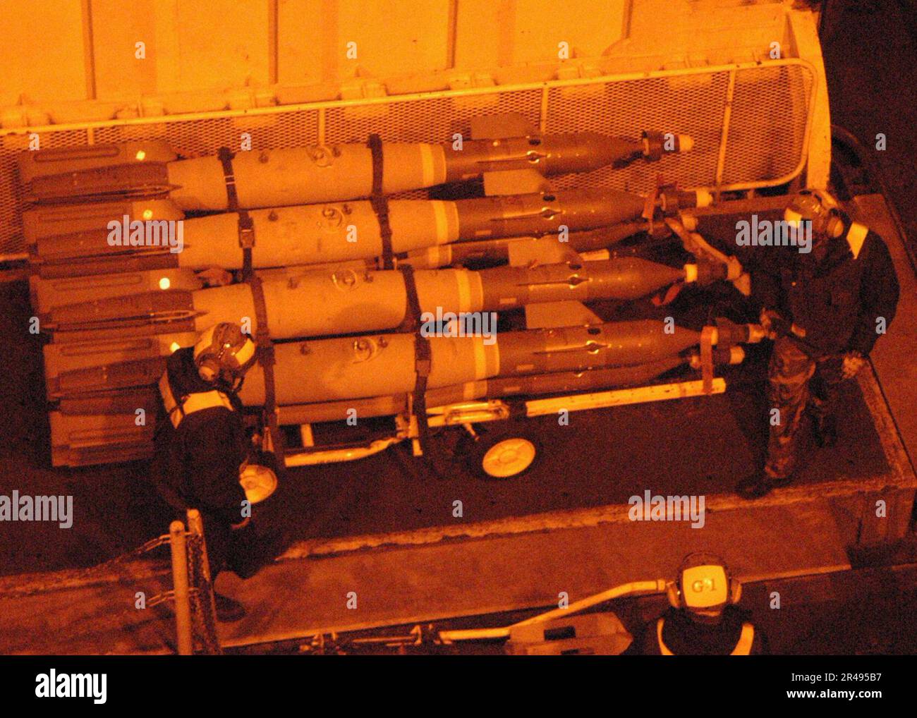 US Navy Aviation Ordnancemen move bombs from a flight deck elevator to ...