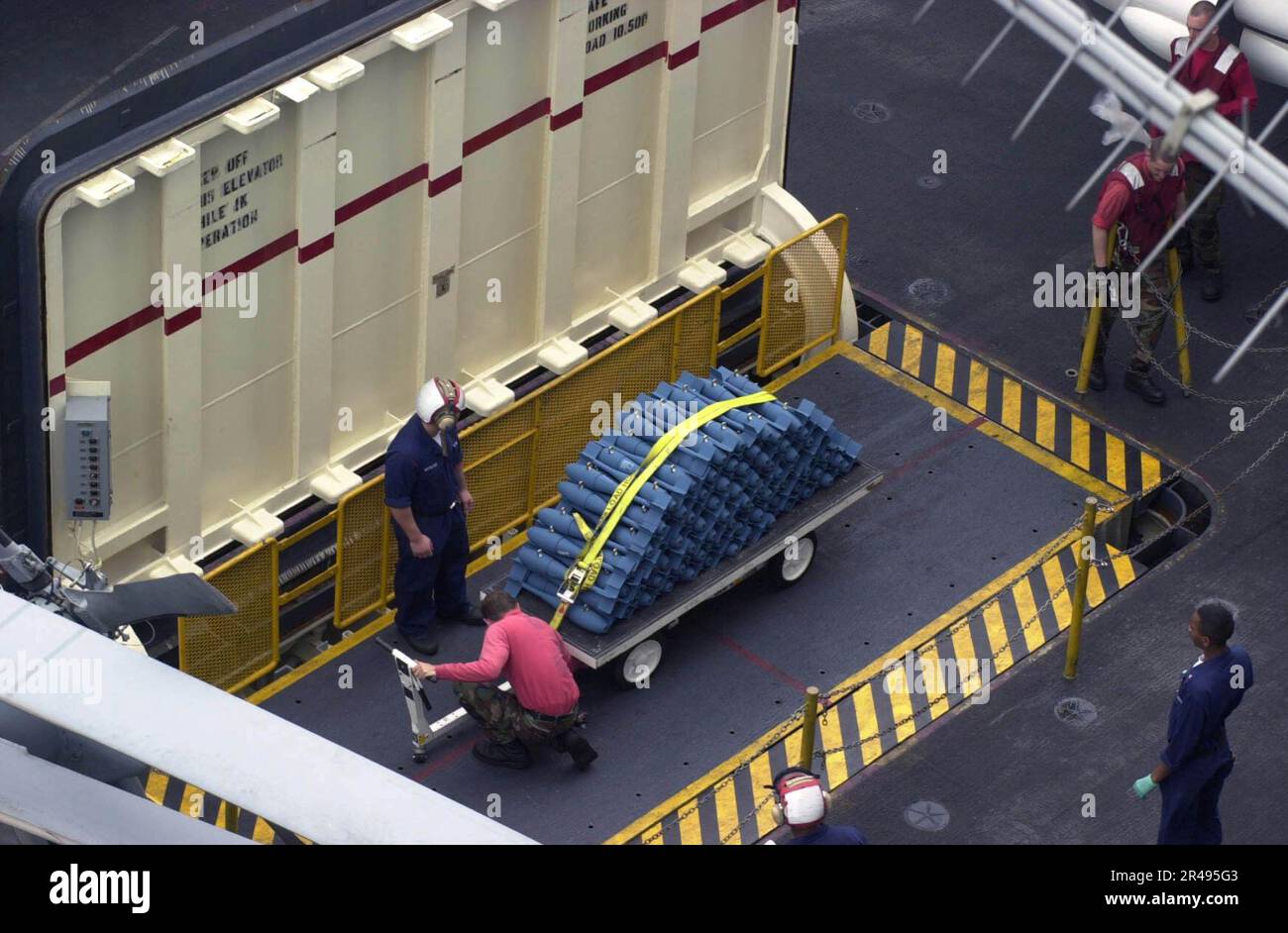 US Navy Sailors transfer MK-76 practice bombs on the weapons elevator ...