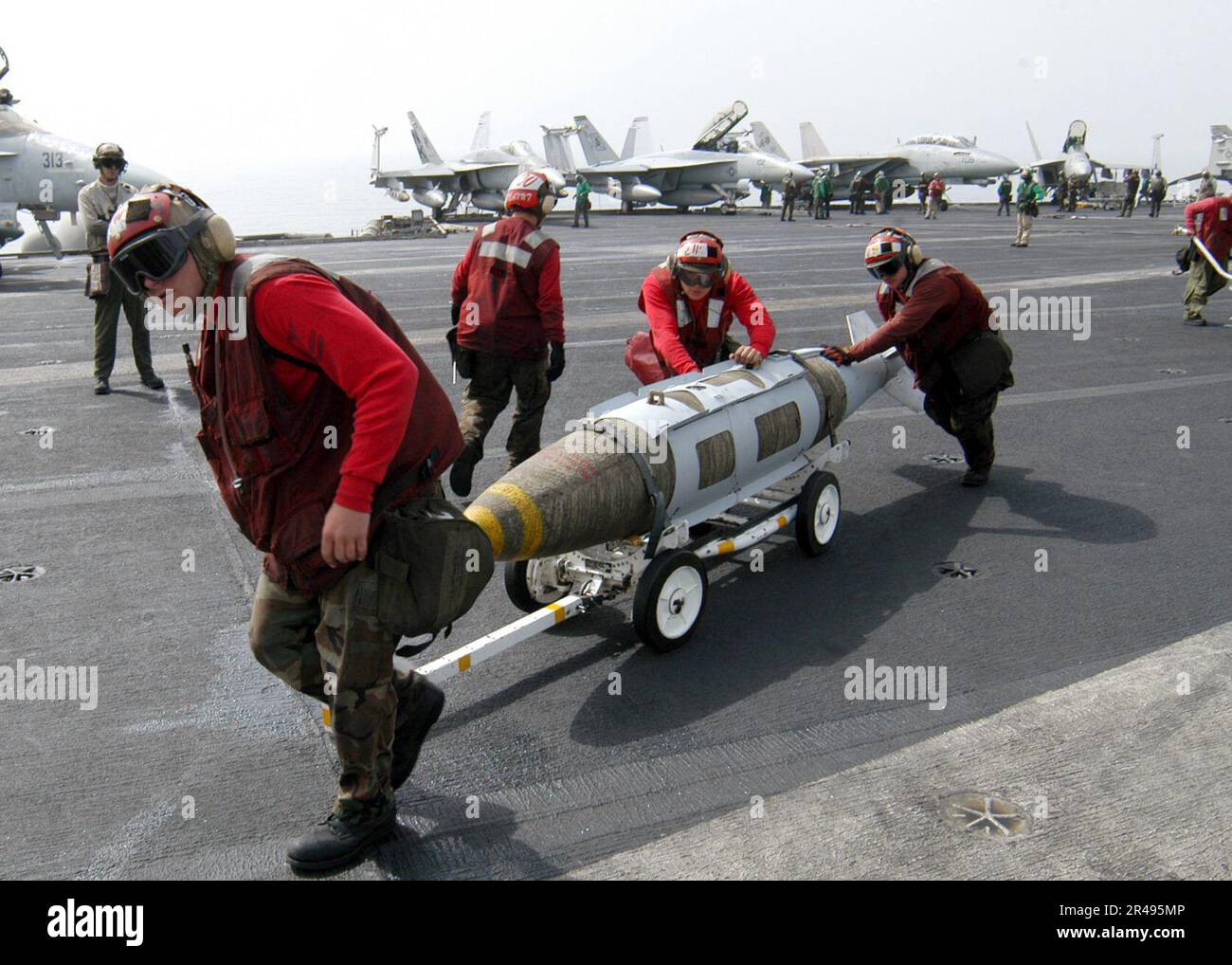 US Navy Aviation Ordnancemen move ordnance on the flight deck aboard ...