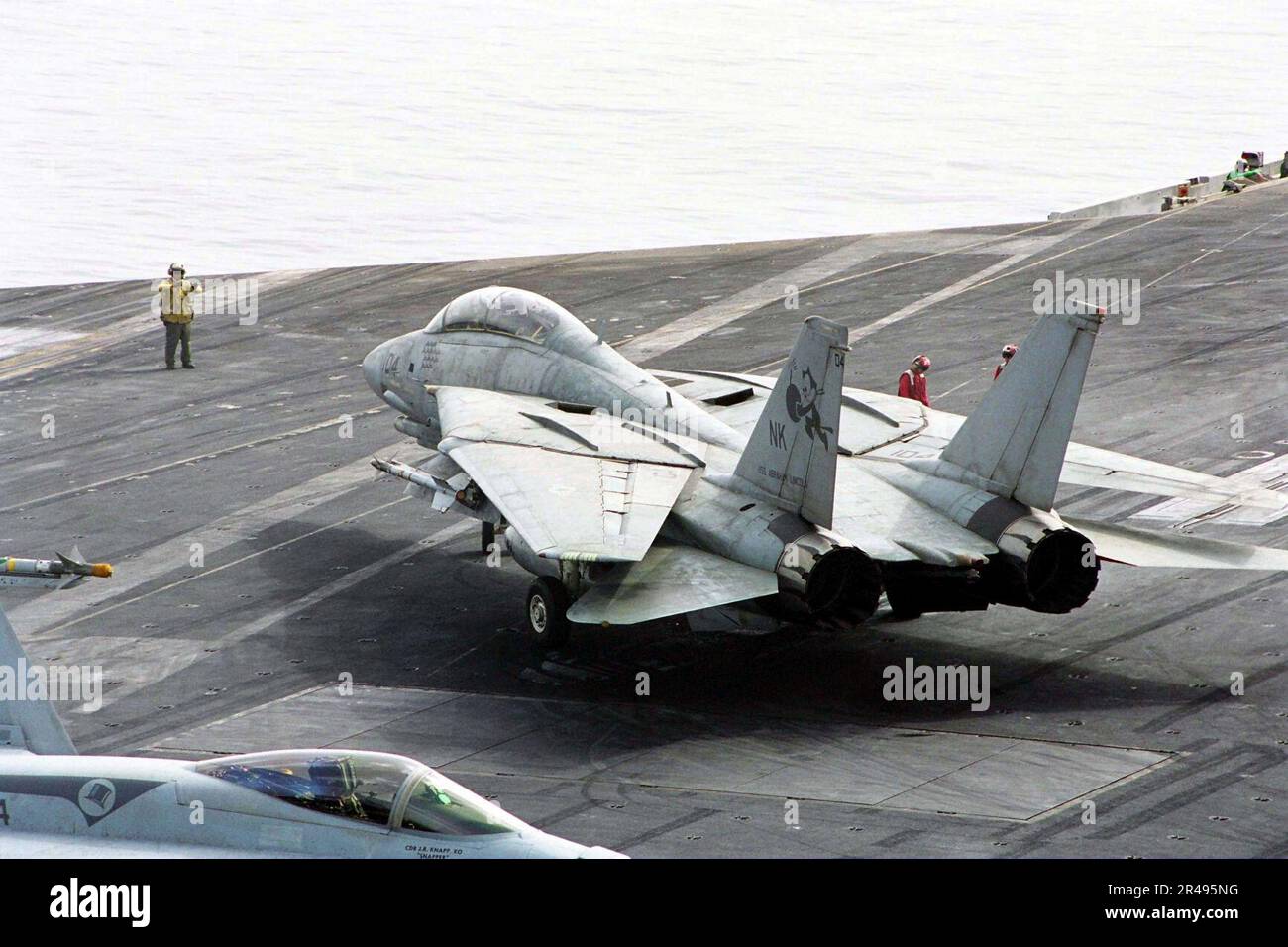 US Navy A flight deck director positions an F-14D Tomcat assigned to ...