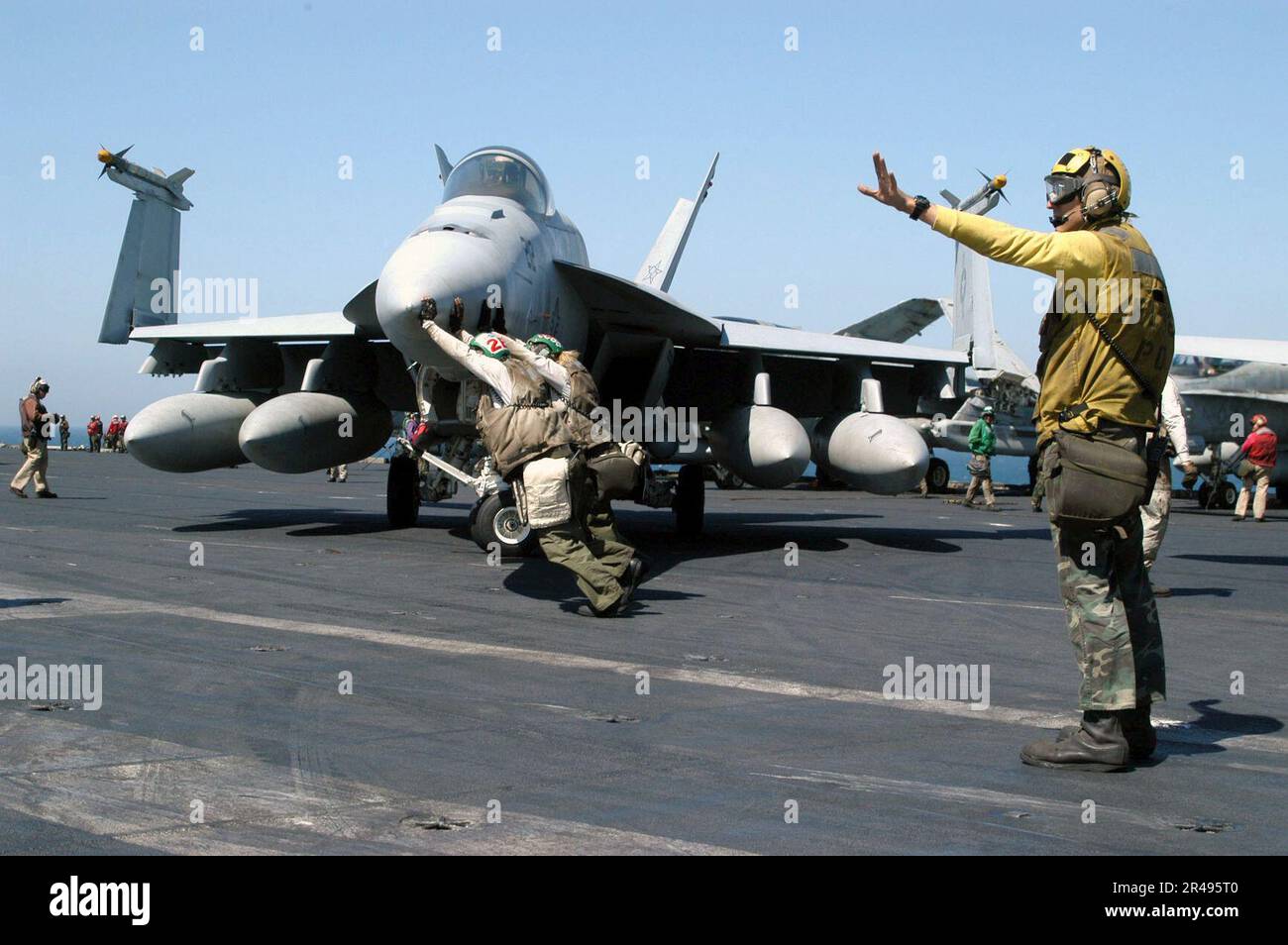 US Navy Sailors push an F-A-18E Super Hornet to aid the handlers in ...