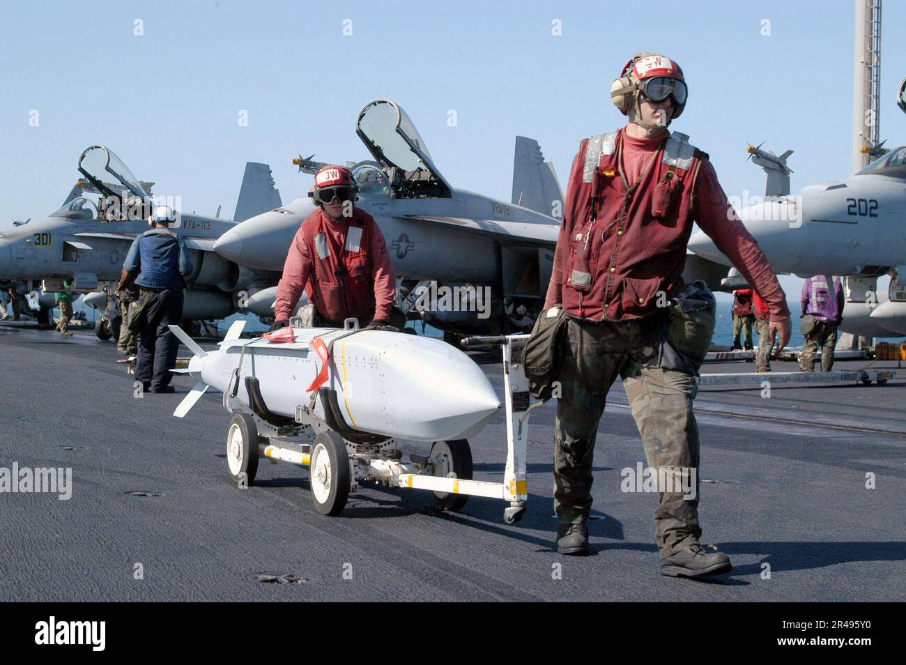US Navy Aviation Ordnancemen move ordnance on the flight deck to nearby ...
