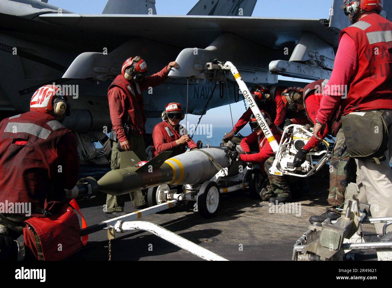US Navy Aviation Ordnancemen load a GBU-16, 1000 lb. bomb onto an F-A ...