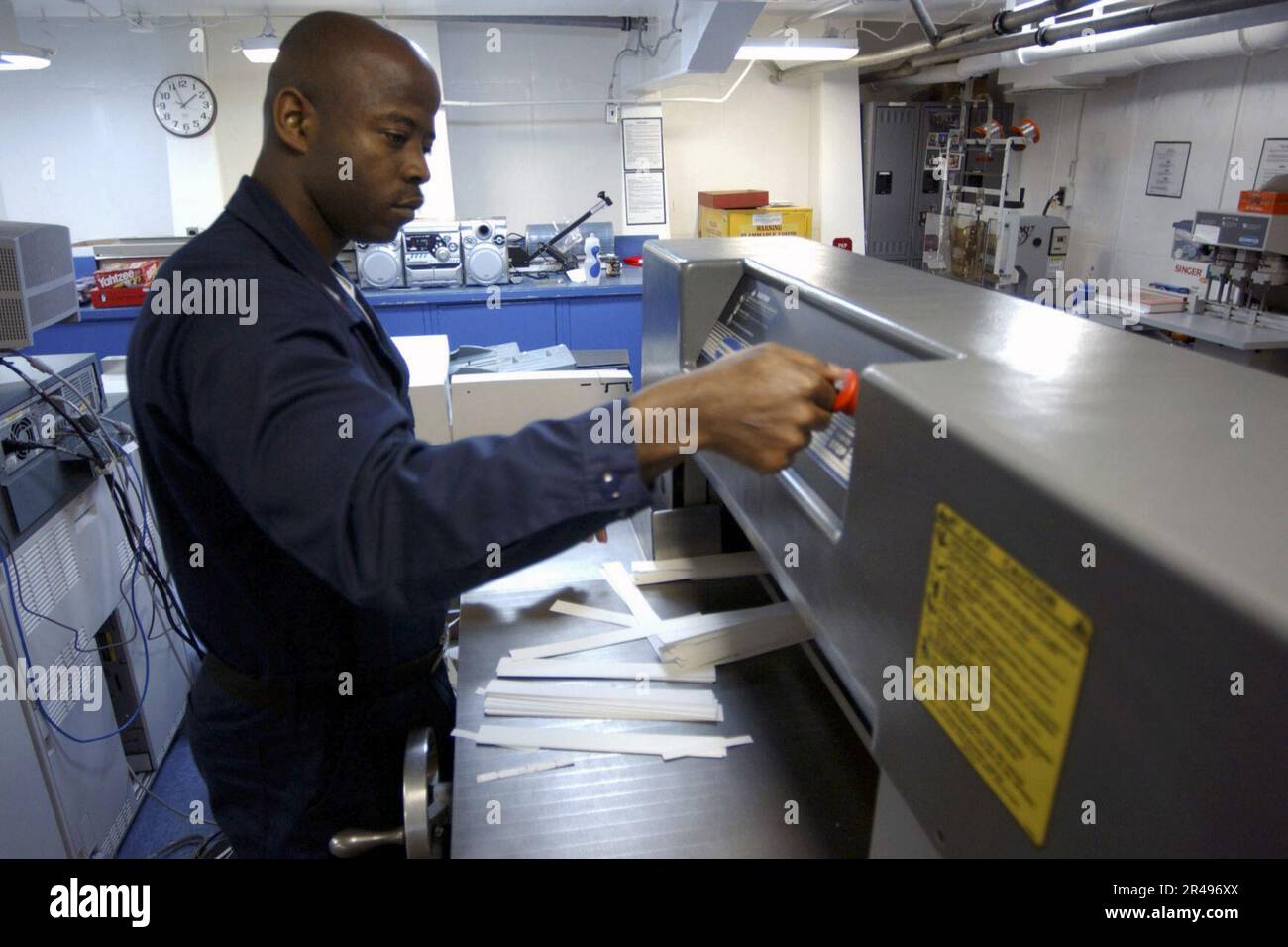 US Navy Lithographers 1st Class cuts paper in the Print Shop aboard USS ...