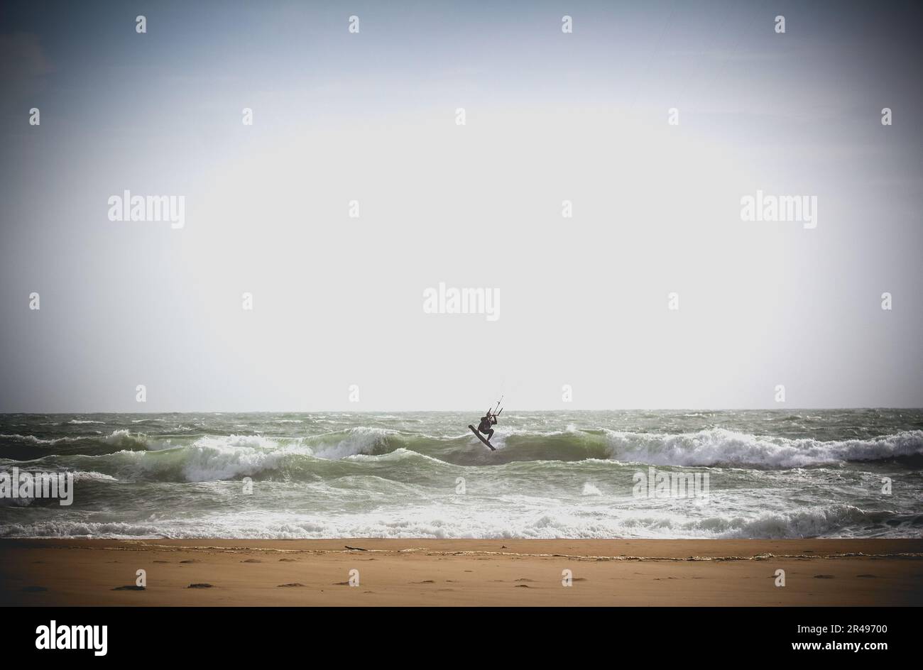 A man enjoying a windsurfing session, riding the waves of a vast ocean ...