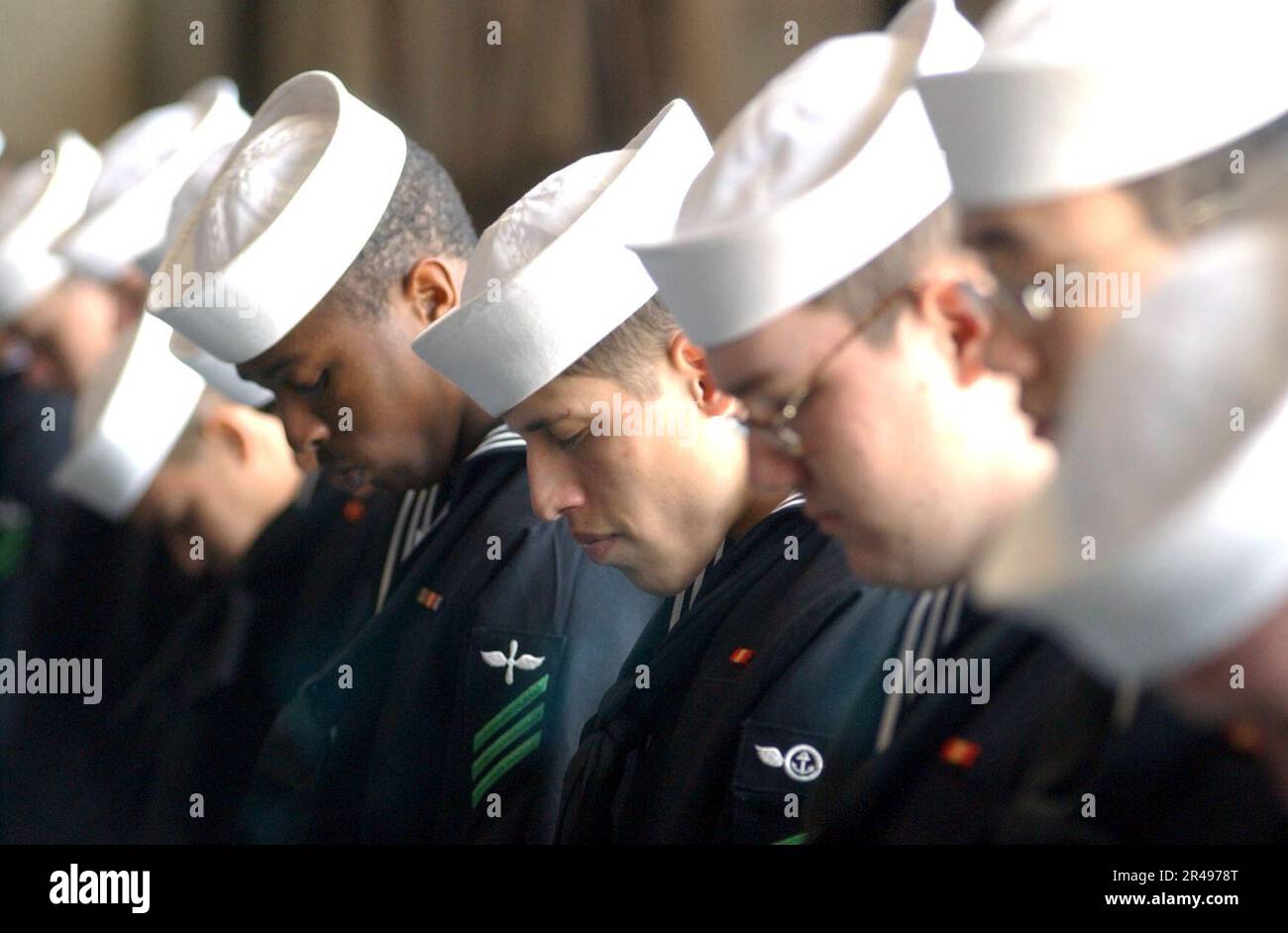 US Navy Sailors bow their heads in prayer during the memorial service ...