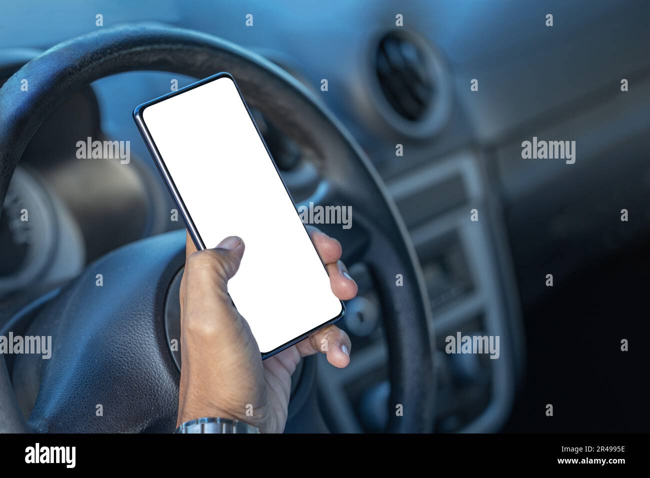 Detail of the hand of a driver holding a mobile phone with a blank ...