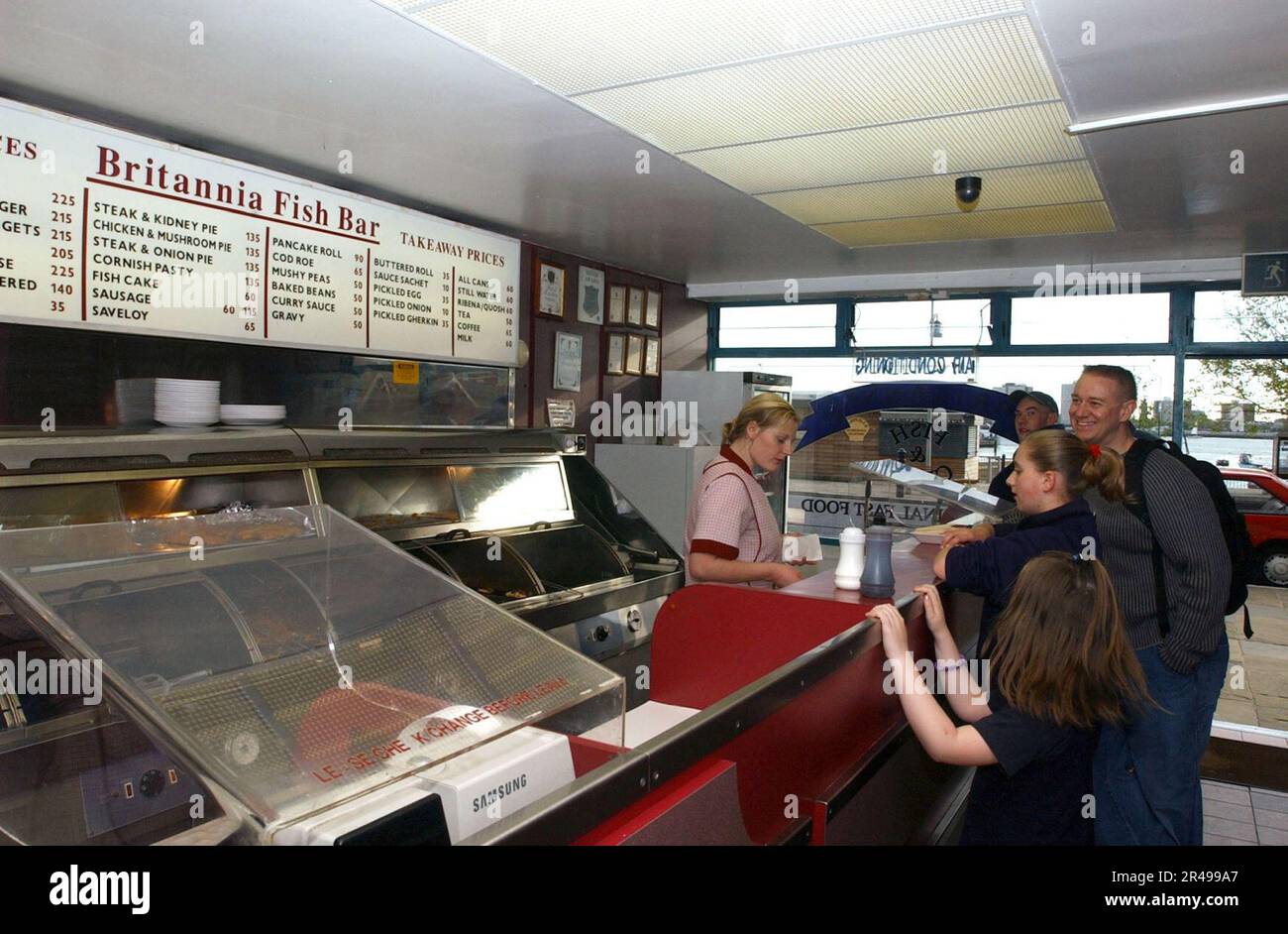 US Navy Photographer's Mate 1st Class orders dinner at a Fish and Chips ...