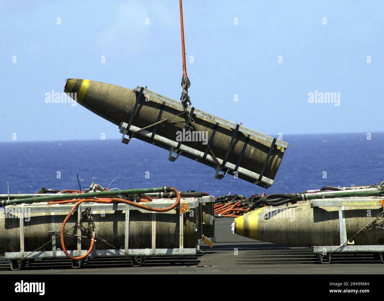 US Navy 2,000-lb. bombs are offloaded from the flight deck aboard USS ...