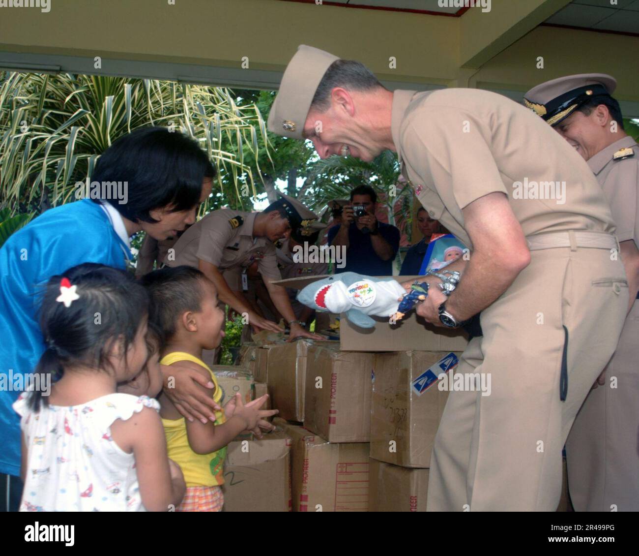 US Navy Rear Adm. Rick Ruehe plays with a child while handing out toys ...