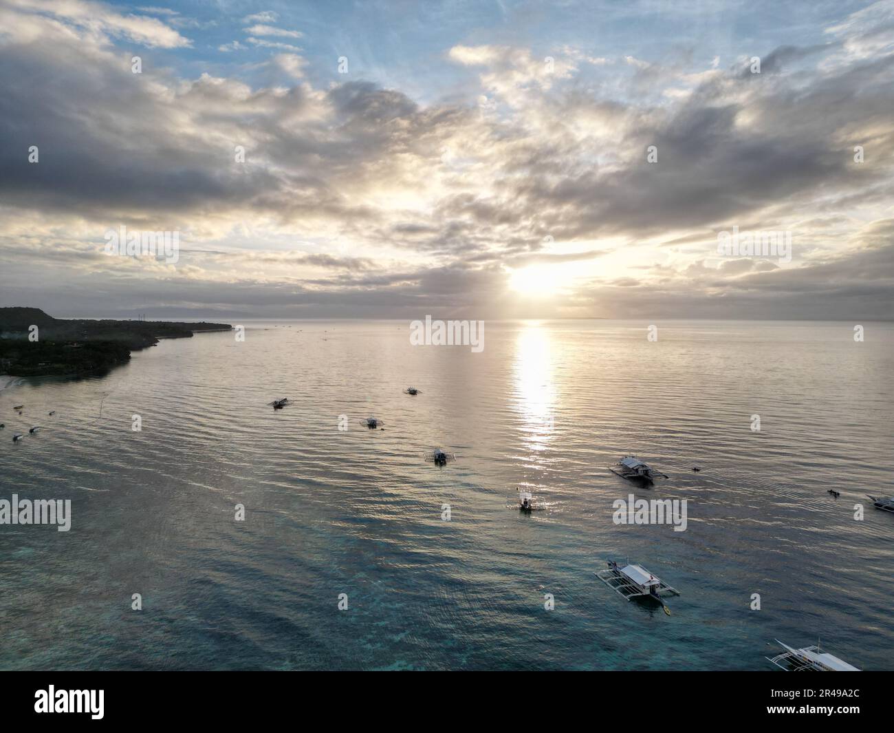 An aerial view of a fleet of sailboats drifting in sea at sunset in ...