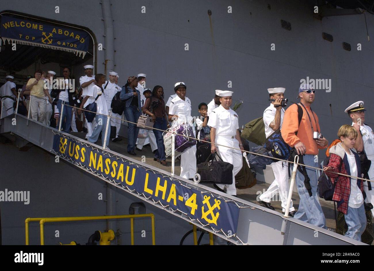 US Navy Sailors and family members depart the amphibious assault ship ...