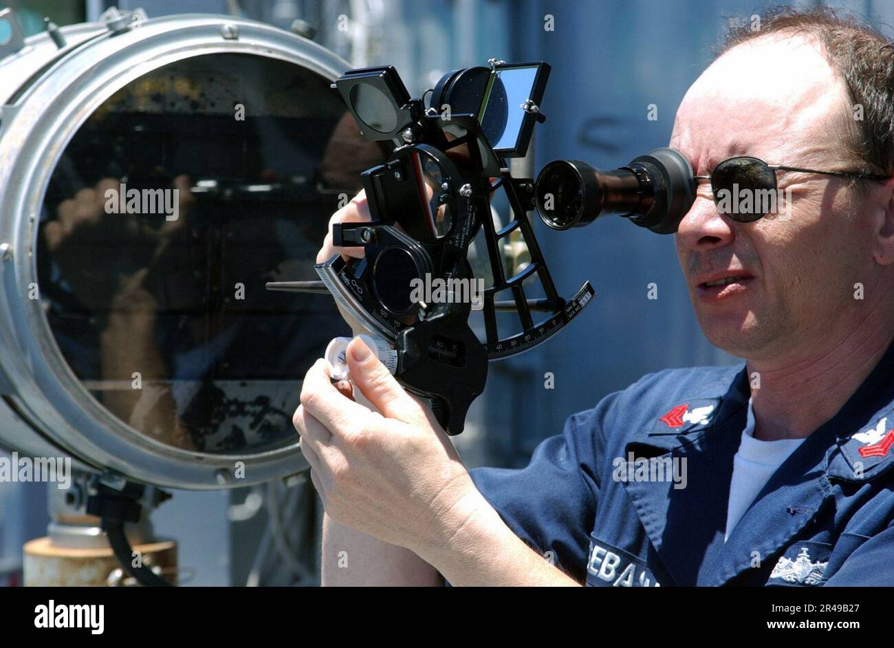 US Navy Quarter Master 1st Class uses a sextant while approaching another ship to calculate the ...
