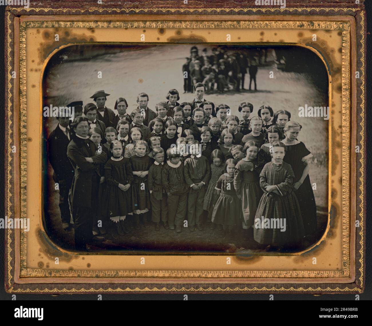 Large group of school children, with their teacher, standing in a town ...