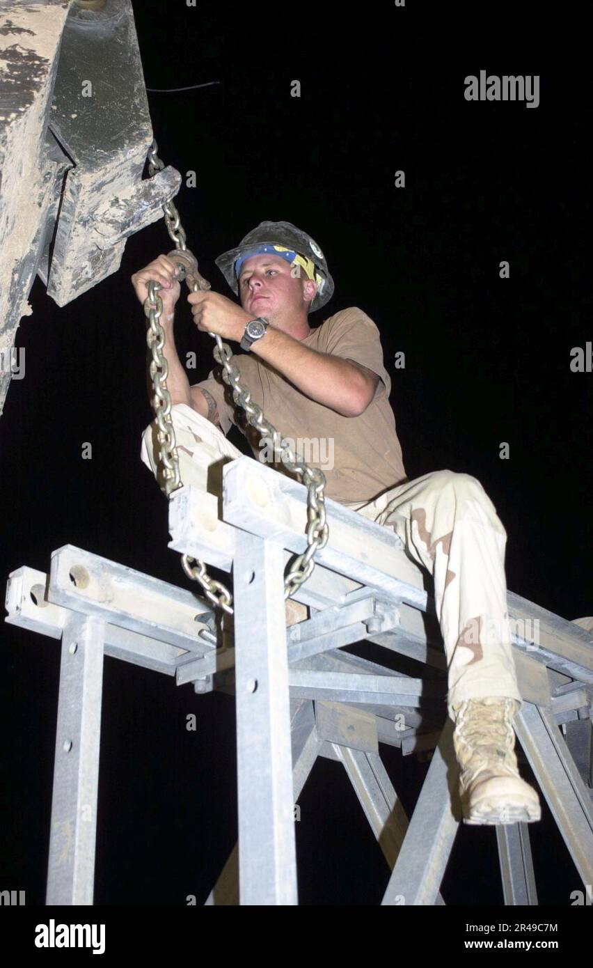 US Navy Builder Constructionman Joey Ledbetter attaches a newly ...