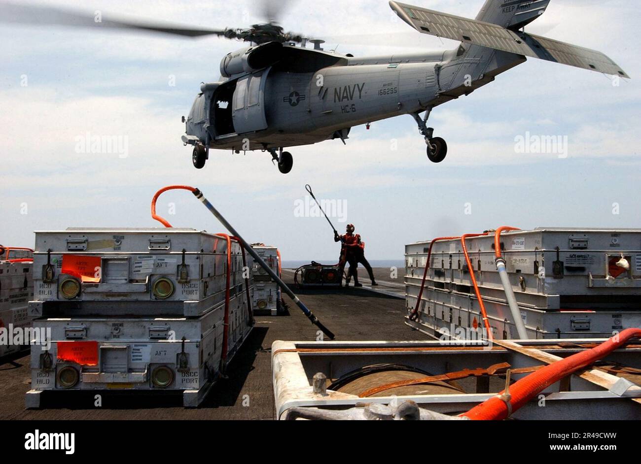 US Navy Aviation Ordanancemen hook up artillery storage bins to an MH ...