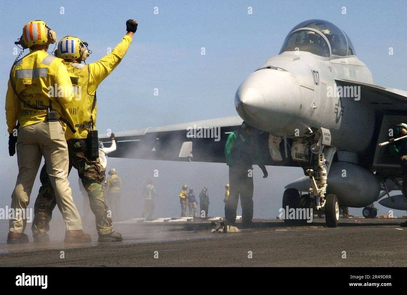 US Navy Aviation Boatswain's Mates signal to the pilot of an F-A-18F ...